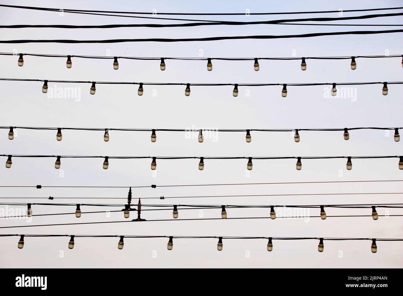 Image of several wires with street light bulbs passing in front of a ...