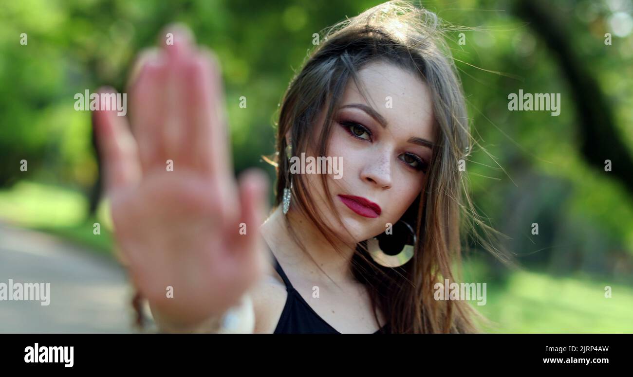 Attractive young woman blocking with hand and gesturing NO with finger ...