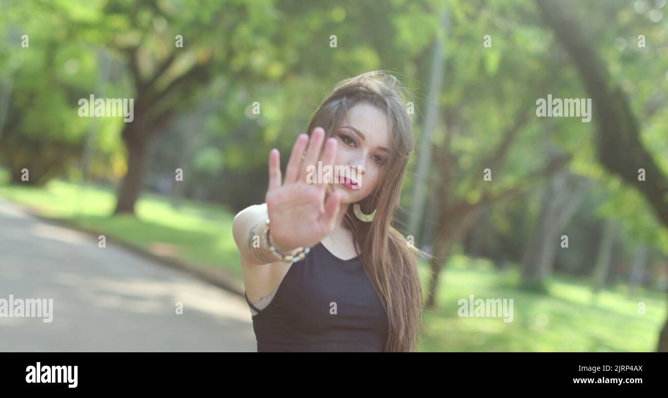 Attractive young woman blocking with hand and gesturing NO with finger ...