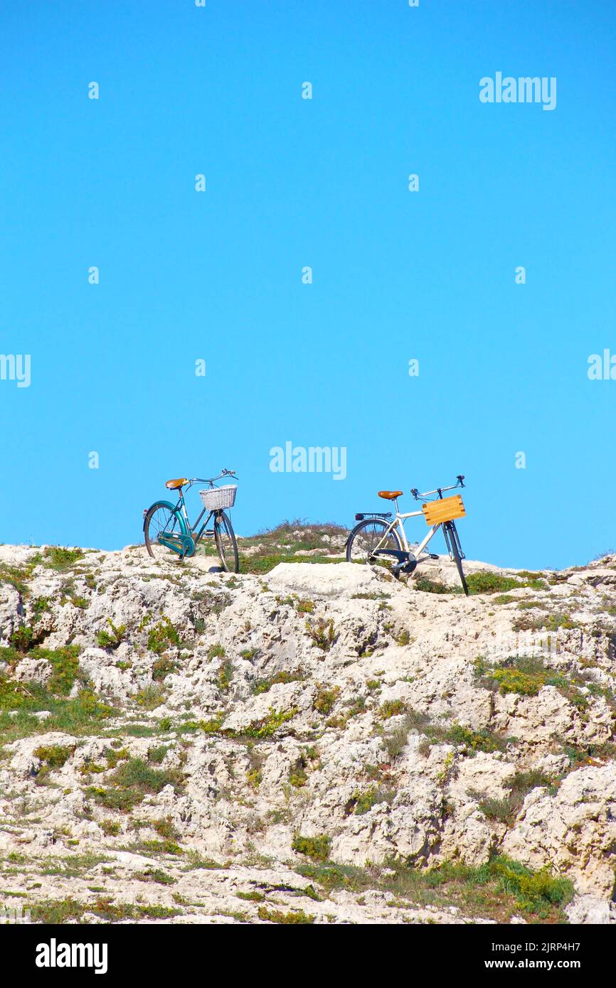 Colored retro bicycles resting on a light-colored stone and in the ...