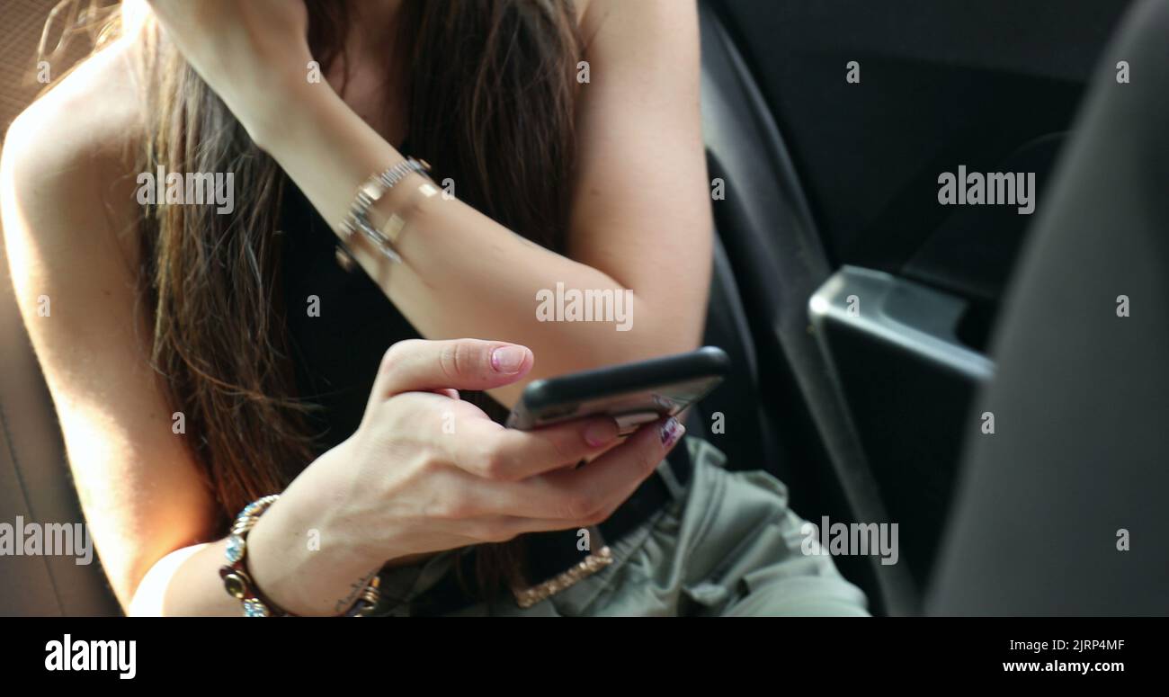Closeup of girl hands texting and using smartphone device while in back ...