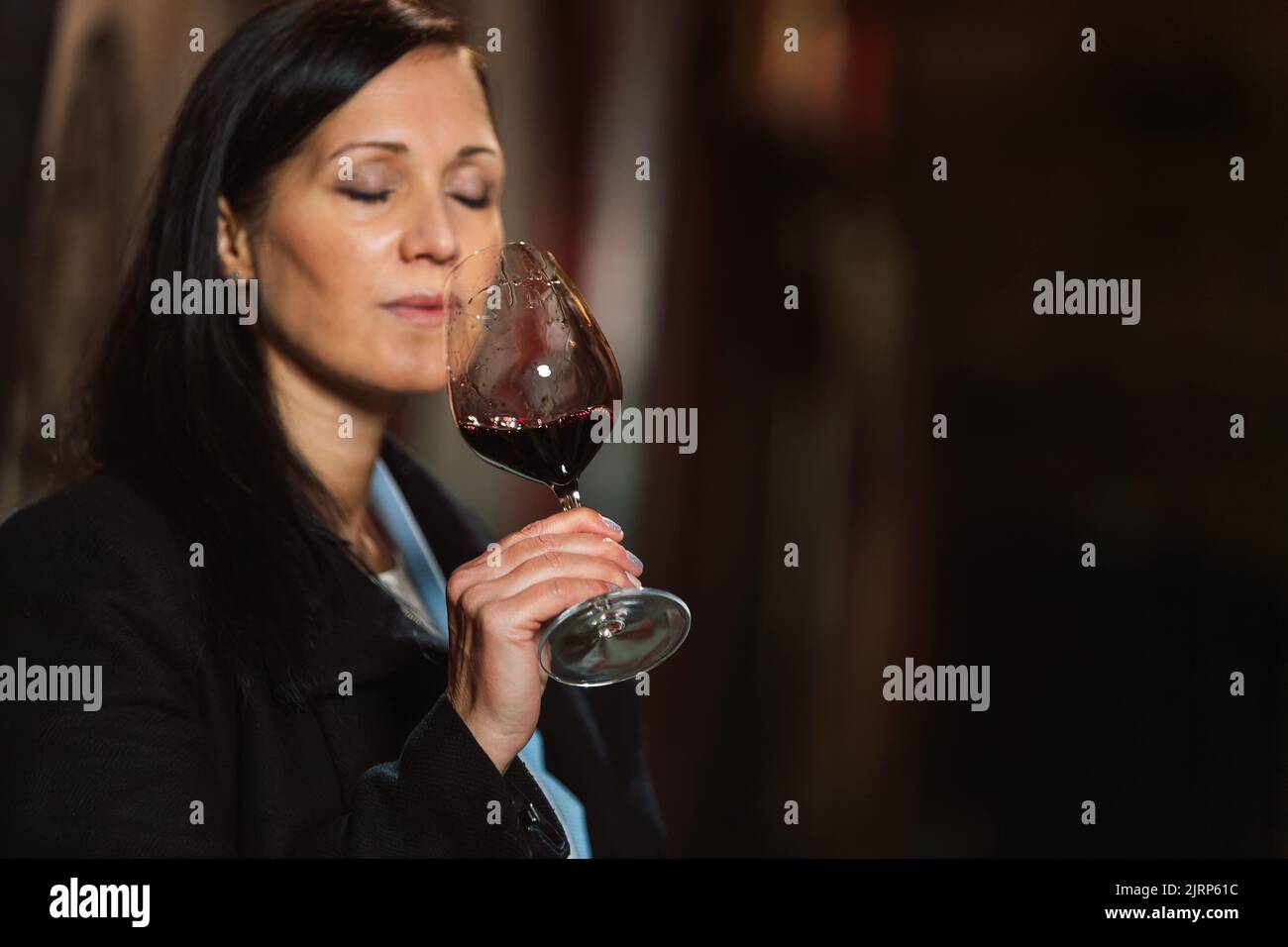 Woman tasting wine at the wine cellar with barrels in background Stock ...