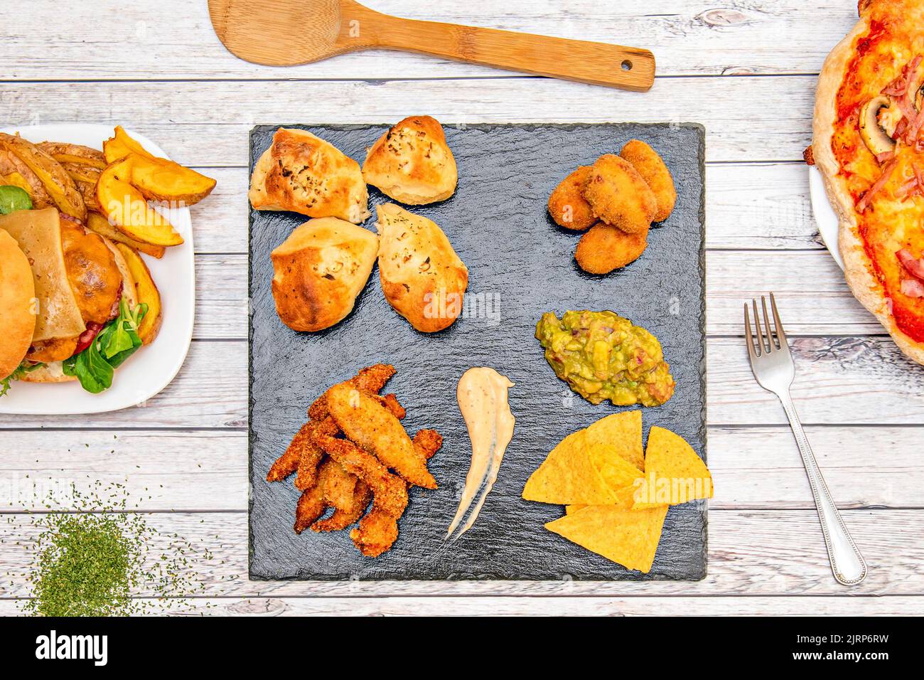 A black slate tray with international appetizers, Spanish croquettes ...