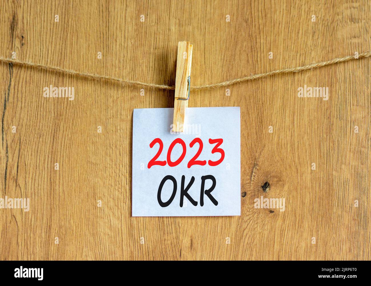 OKR objectives and key results symbol. White paper with words OKR 2023 clip on wooden clothespin ...