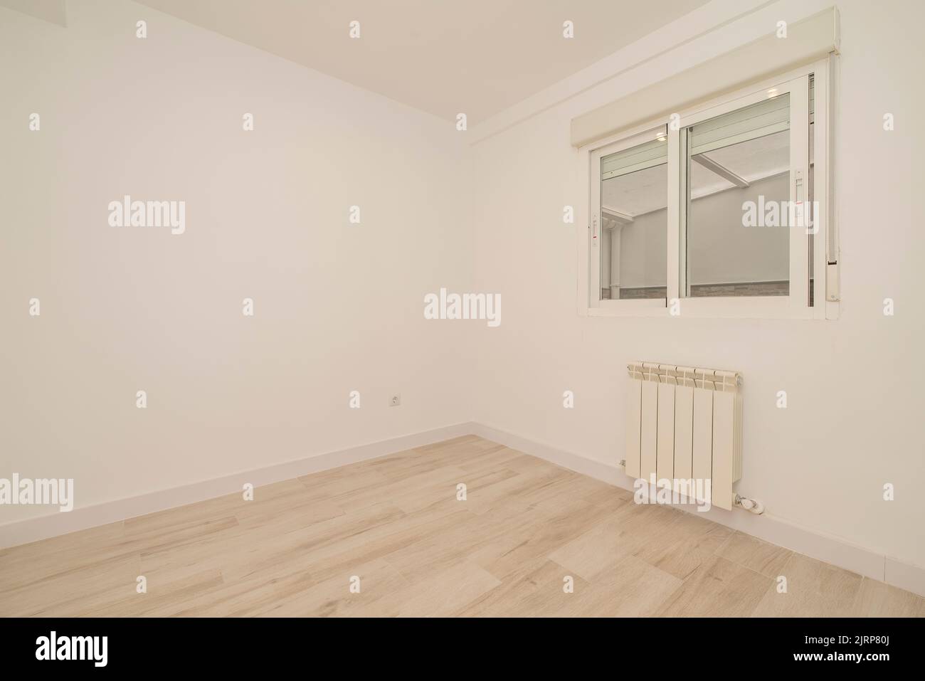 Empty living room with light wooden floorboards, white radiator on the ...
