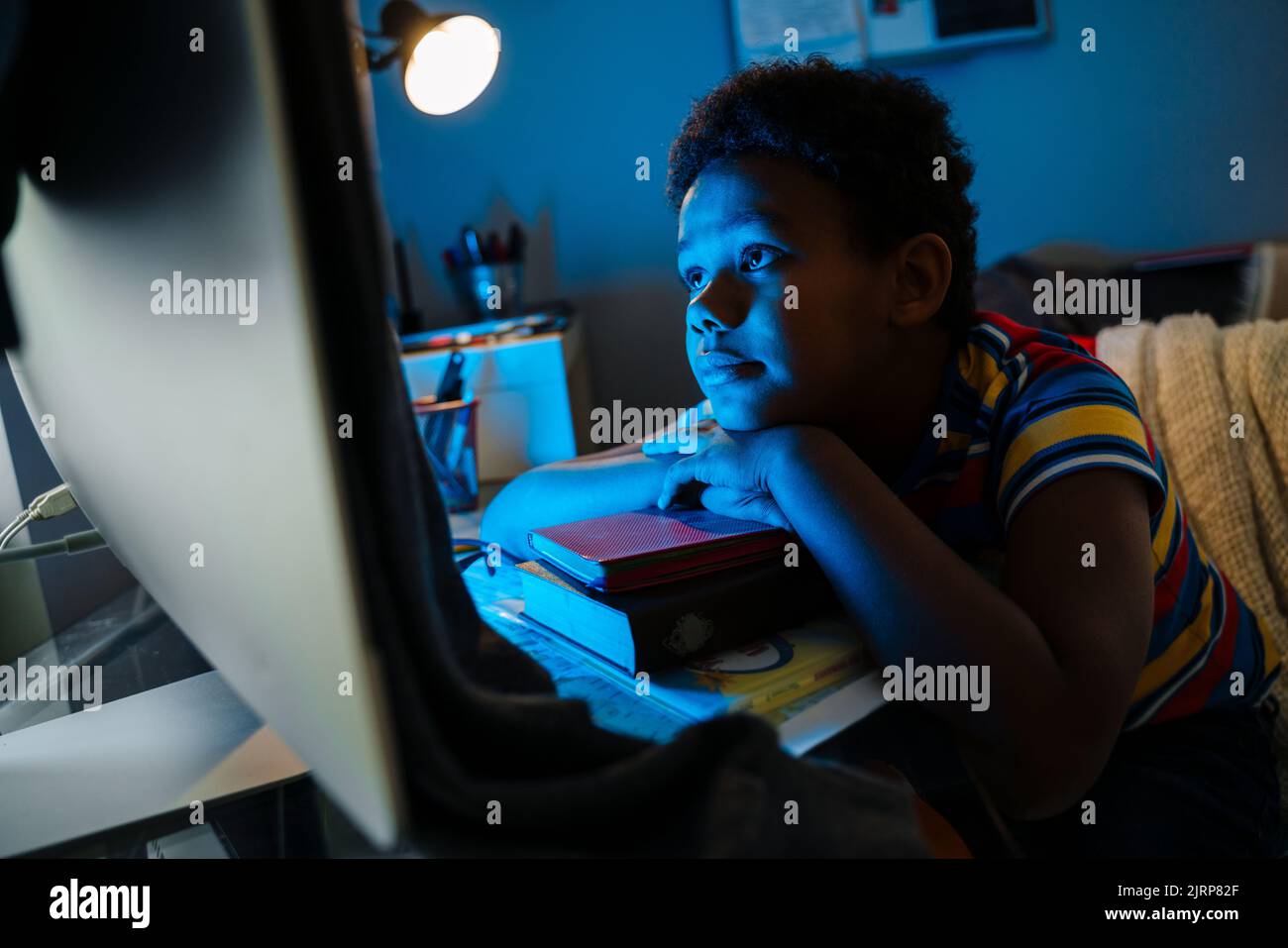 Black boy looking at computer screen while doing homework at home Stock ...