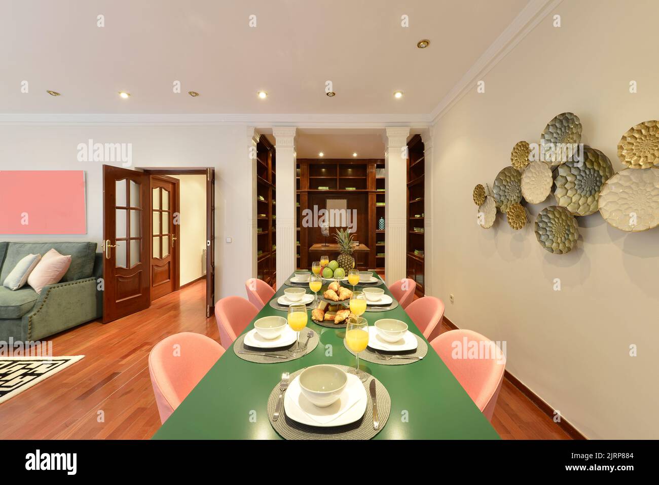 Long plain green dining table with pink velvet upholstered chairs in a ...