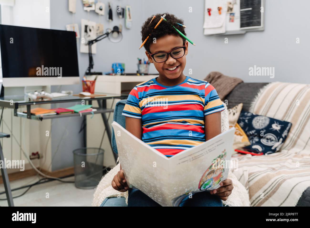 Black boy making fun with pencils while reading book at home Stock ...