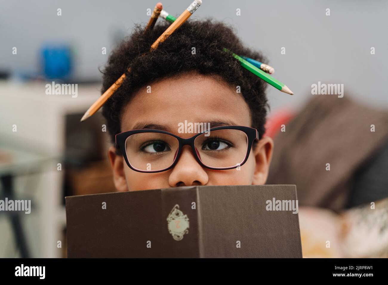 Black boy making fun with pencils while reading book at home Stock ...
