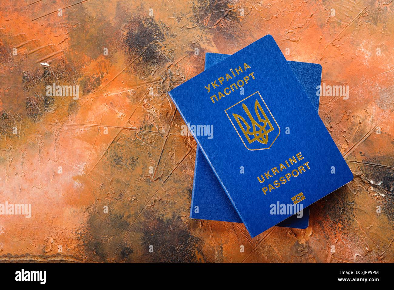 Two blue Ukrainian biometric passports on a black and orange background ...