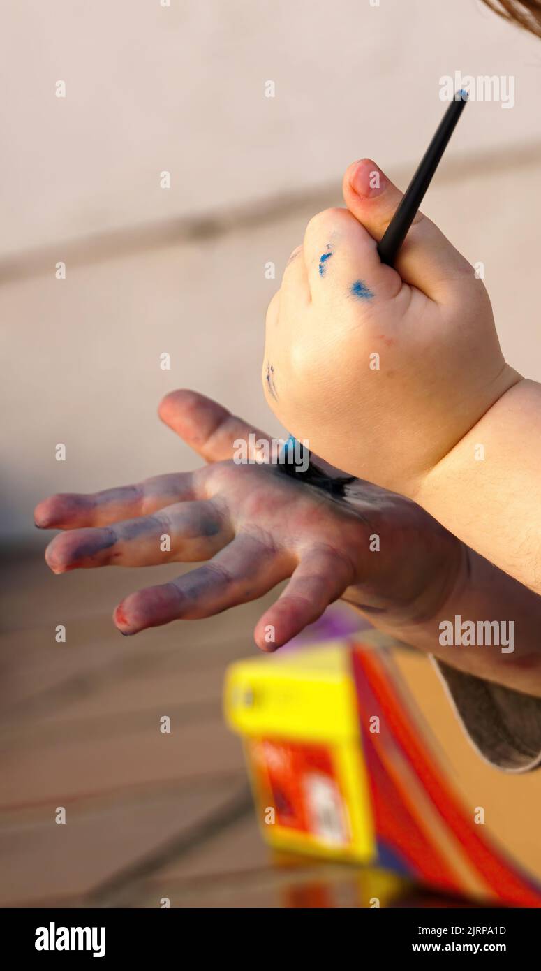 Hands of a child with a brush, painting the palm of his own hand Stock ...