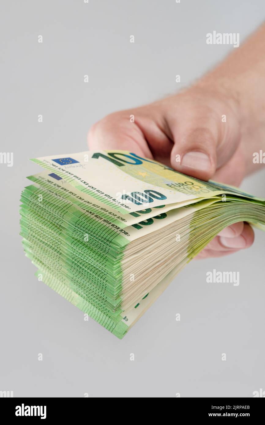 Stack of euro bills in hand. A large stack of 100 euro banknotes in a ...