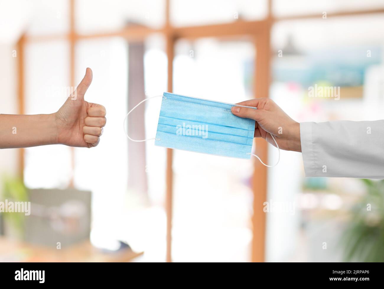 hand with mask and showing thumbs up at office Stock Photo - Alamy