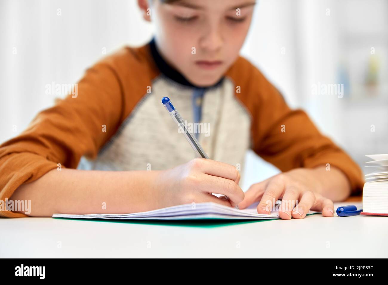 student boy with book writing to notebook at home Stock Photo - Alamy