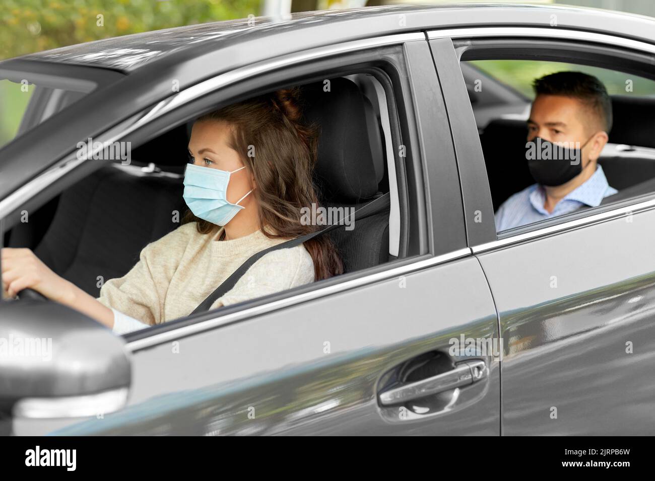 female driver in mask driving car with passenger Stock Photo - Alamy