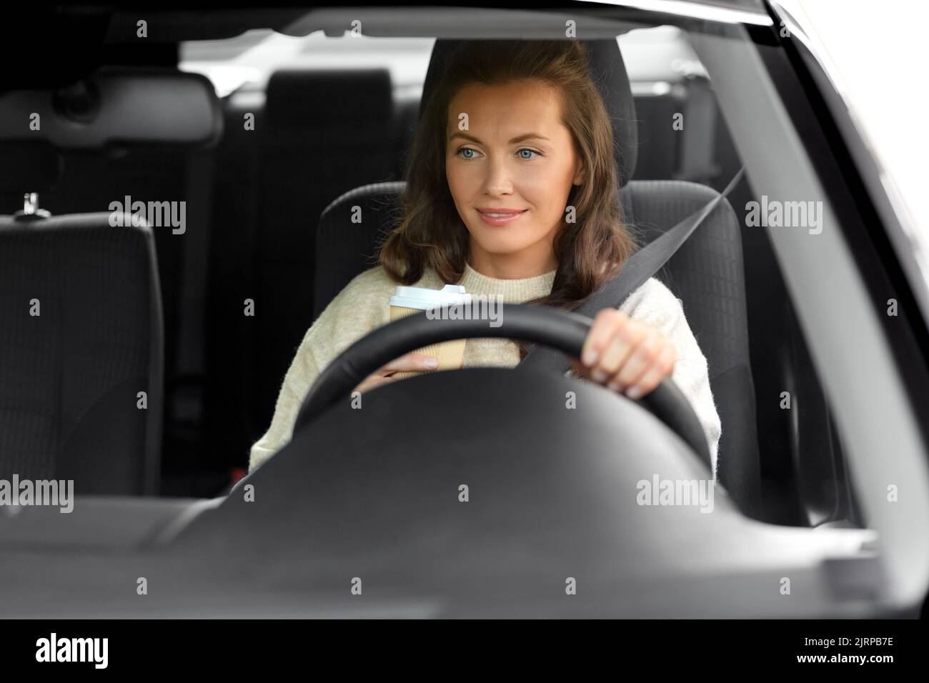 woman or female driver with coffee driving car Stock Photo - Alamy