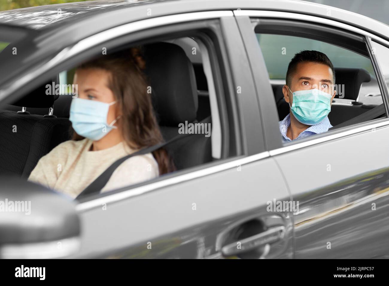 female driver in mask driving car with passenger Stock Photo - Alamy