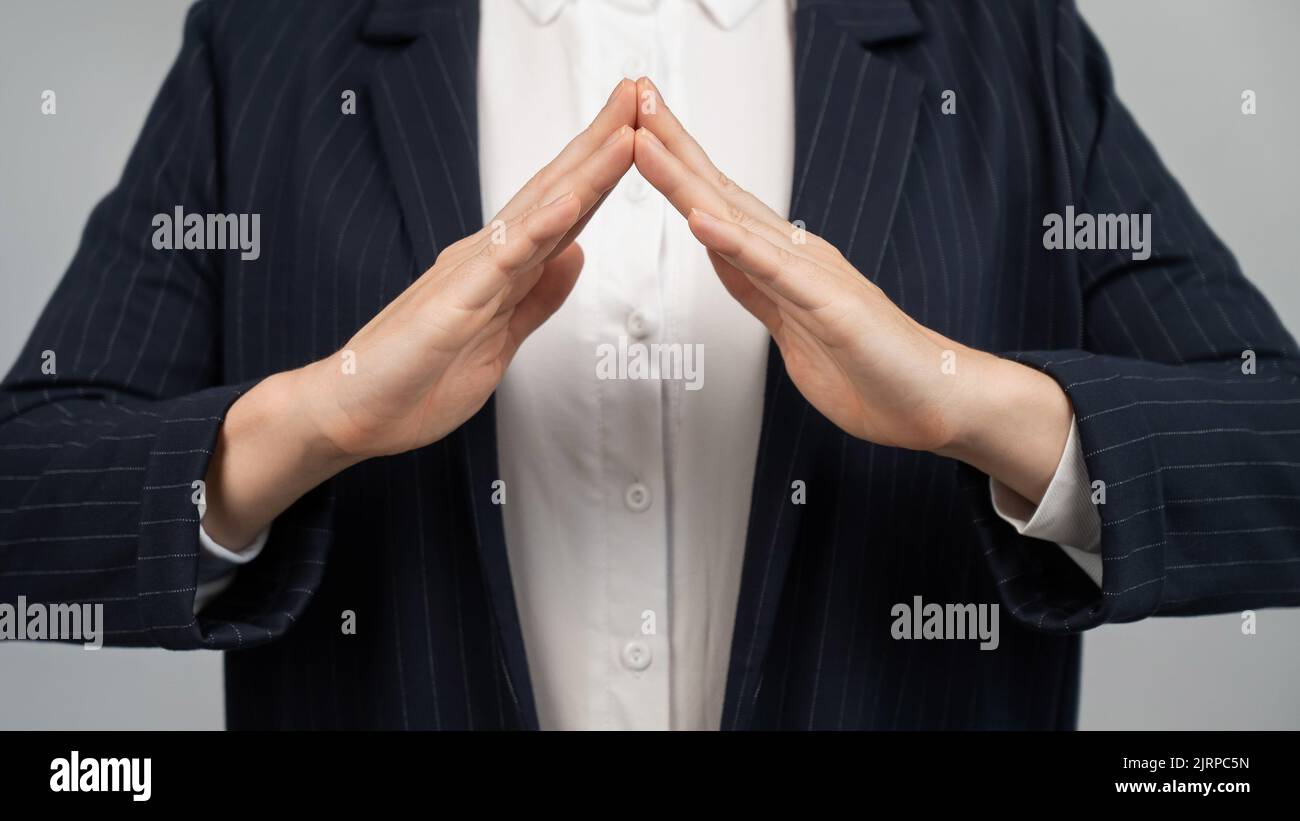Business woman in a suit holding her hands in the shape of a house ...