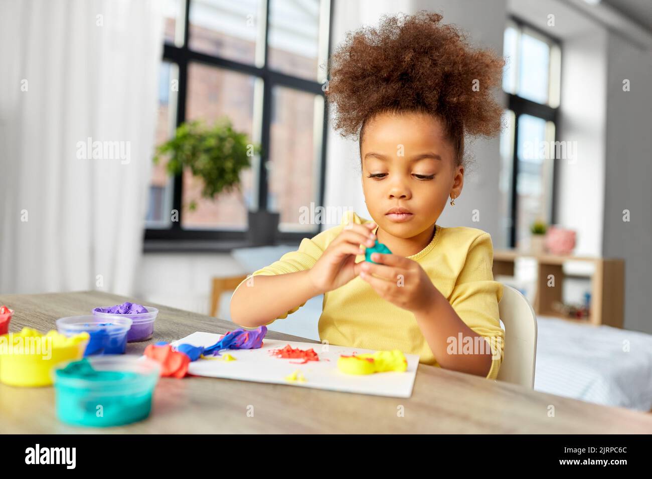 little girl with modeling clay playing at home Stock Photo - Alamy