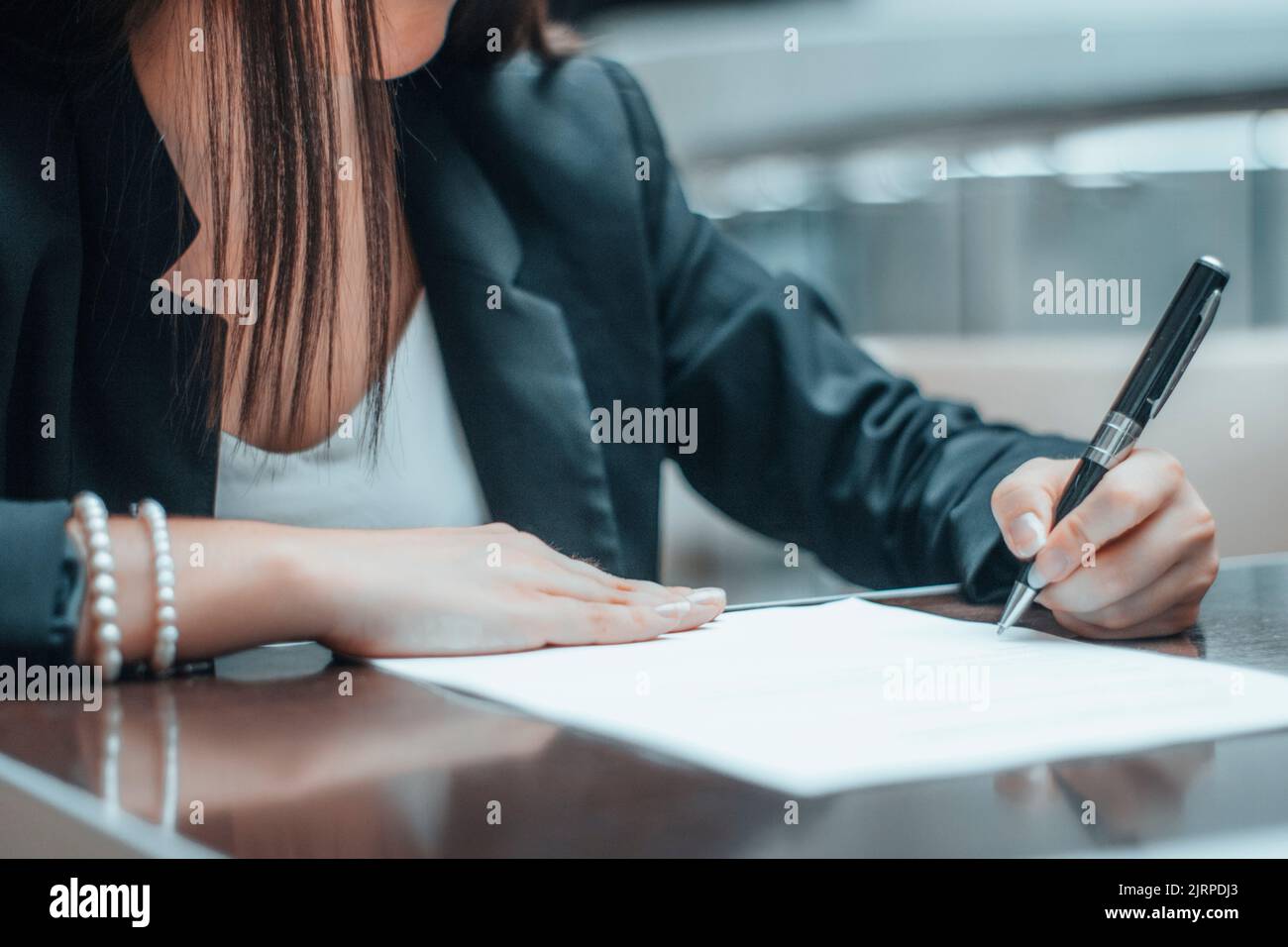 A young woman signs an employment contract on a piece of paper in the ...