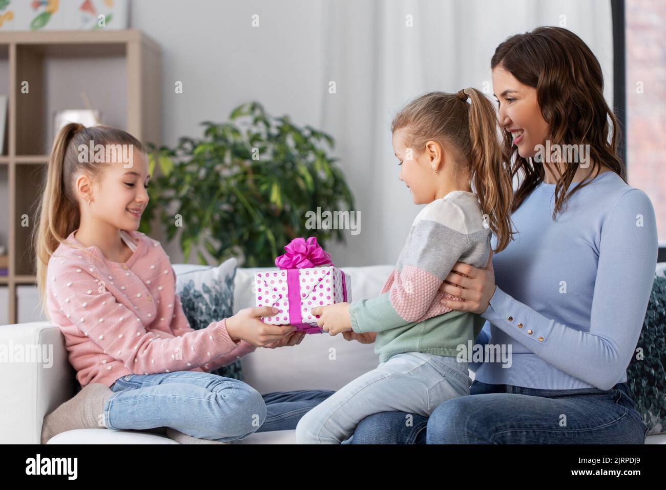 girl giving present to younger sister at home Stock Photo - Alamy
