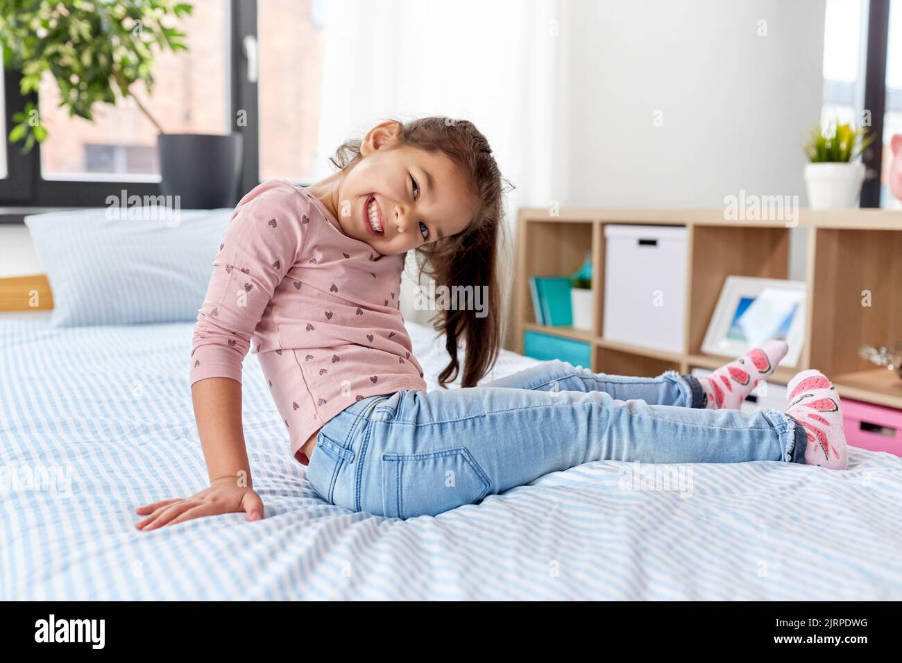 happy smiling little girl sitting on bed at home Stock Photo - Alamy
