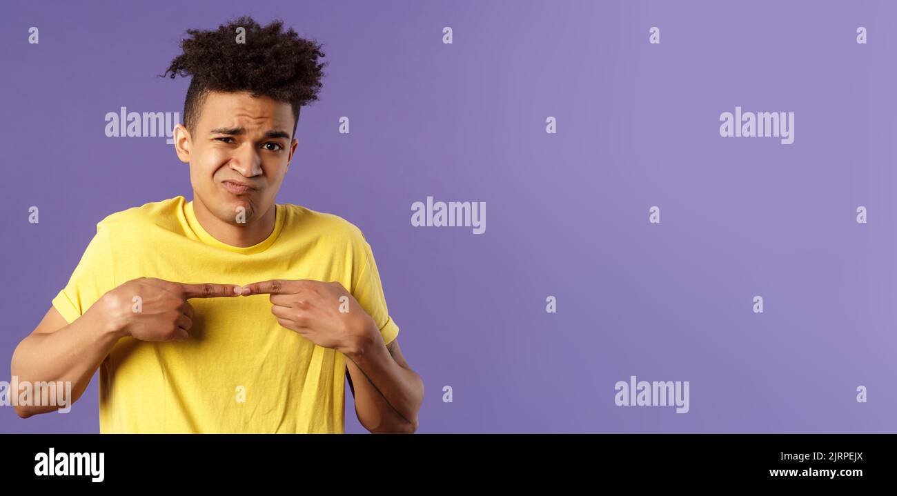 Close-up portrait of shy and modest young silly hispanic man trying say ...