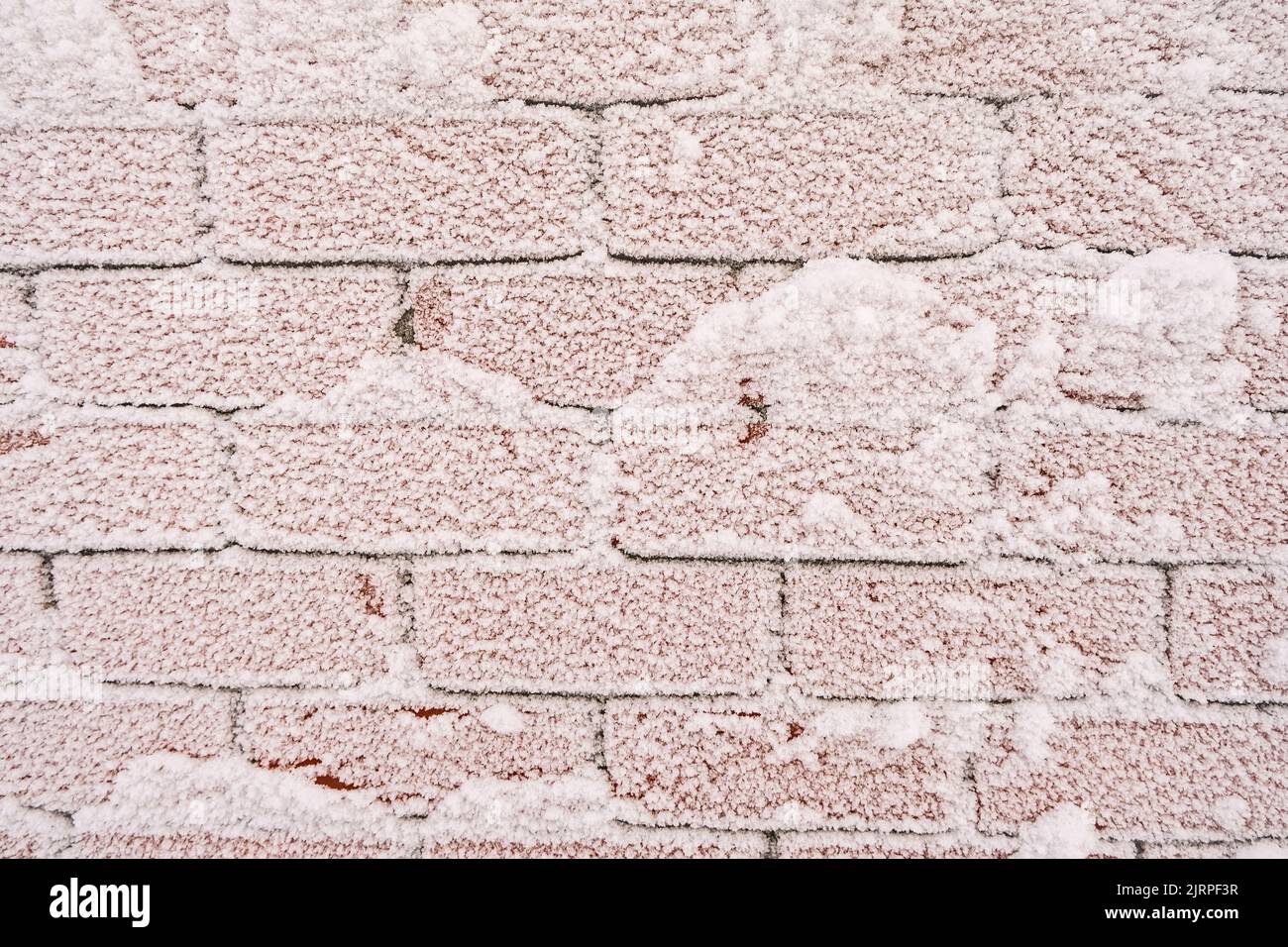 The brick wall is covered with snow patterns. Frost on the brick ...