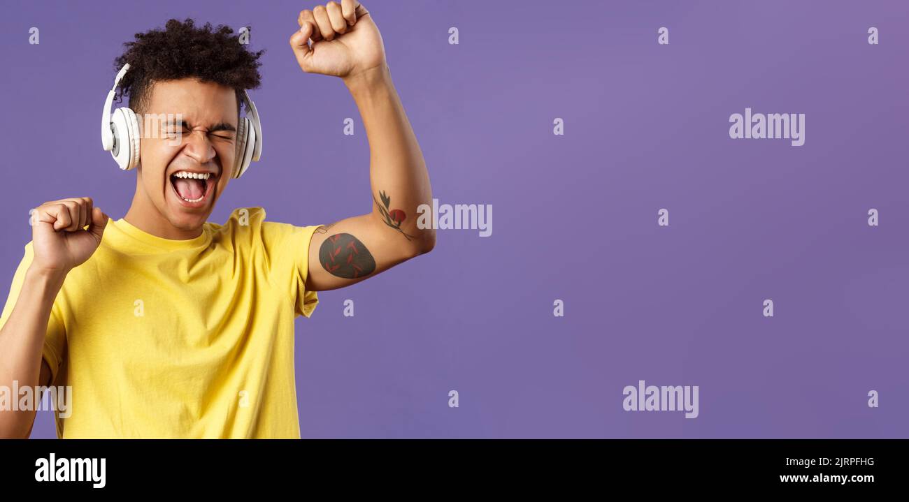 Close-up portrait of cheerful, happy young dancing guy lift hand up ...