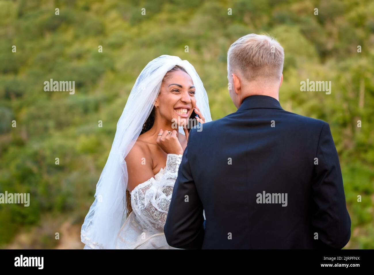Black bride talking on the phone and looking happily at her white ...