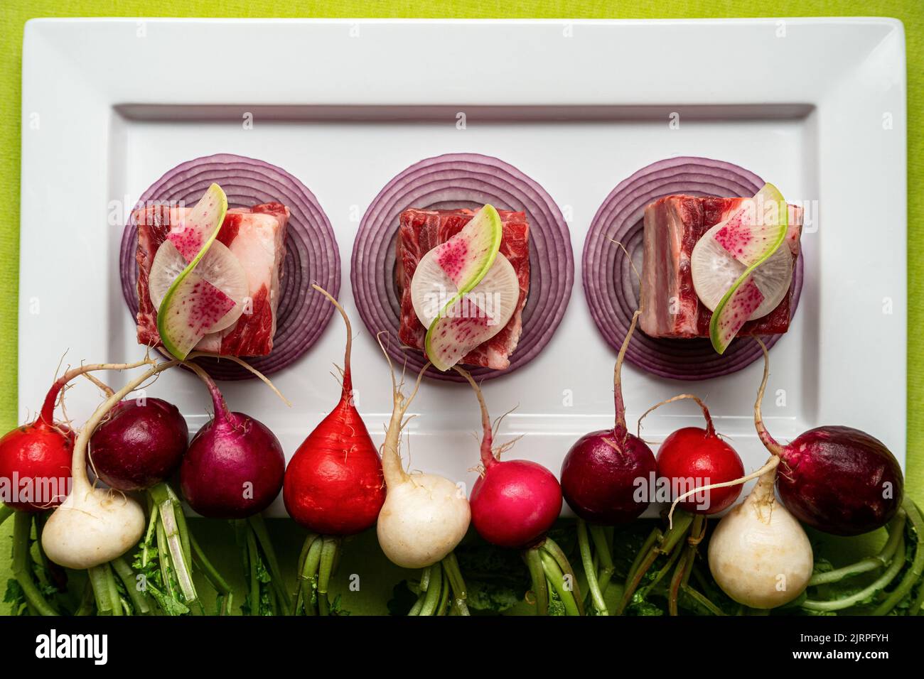 A top view of raw short ribs on raw onions with radishes Stock Photo ...