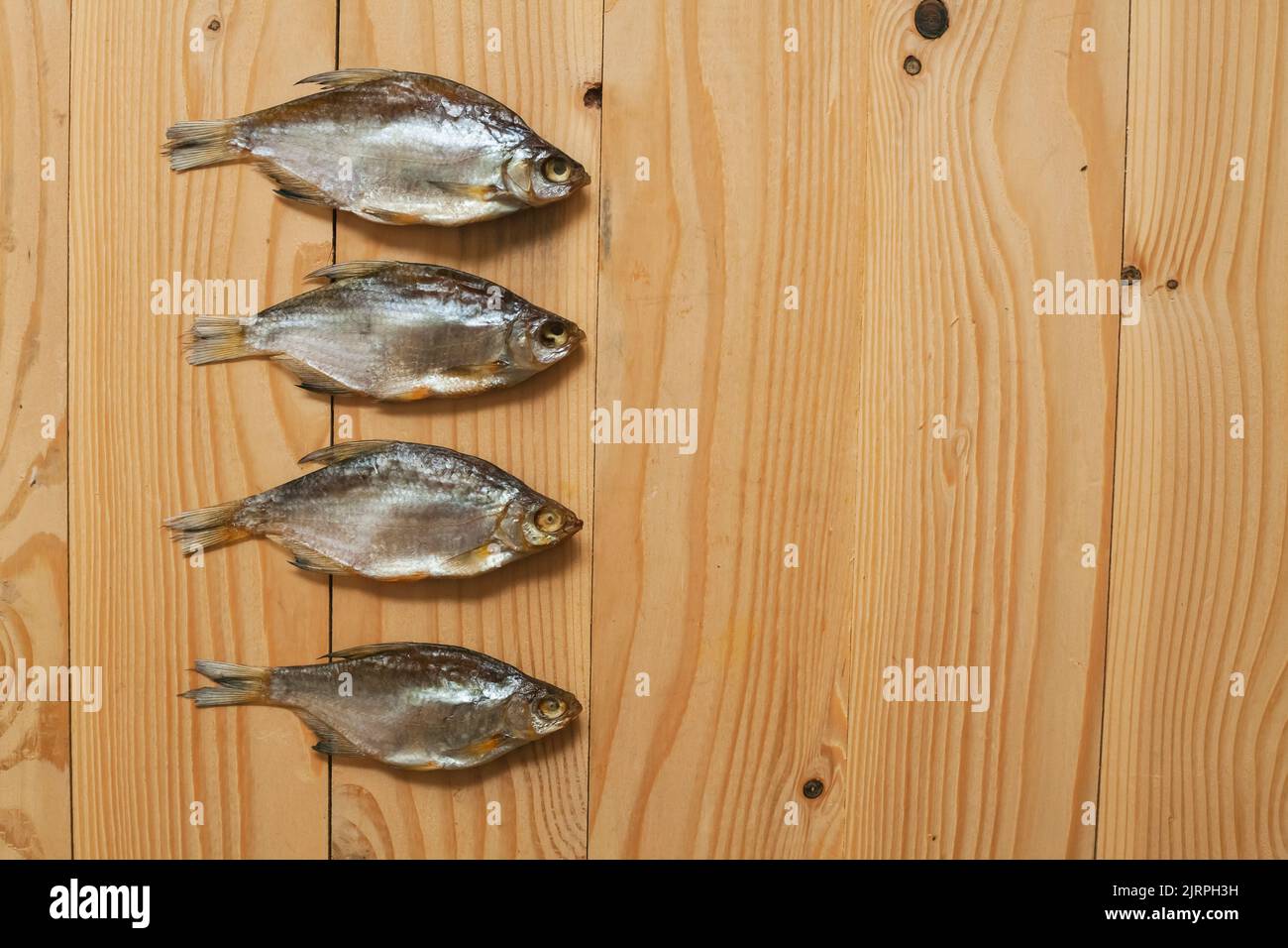 Dried salted fish on a wooden background. The fish is completely salted ...