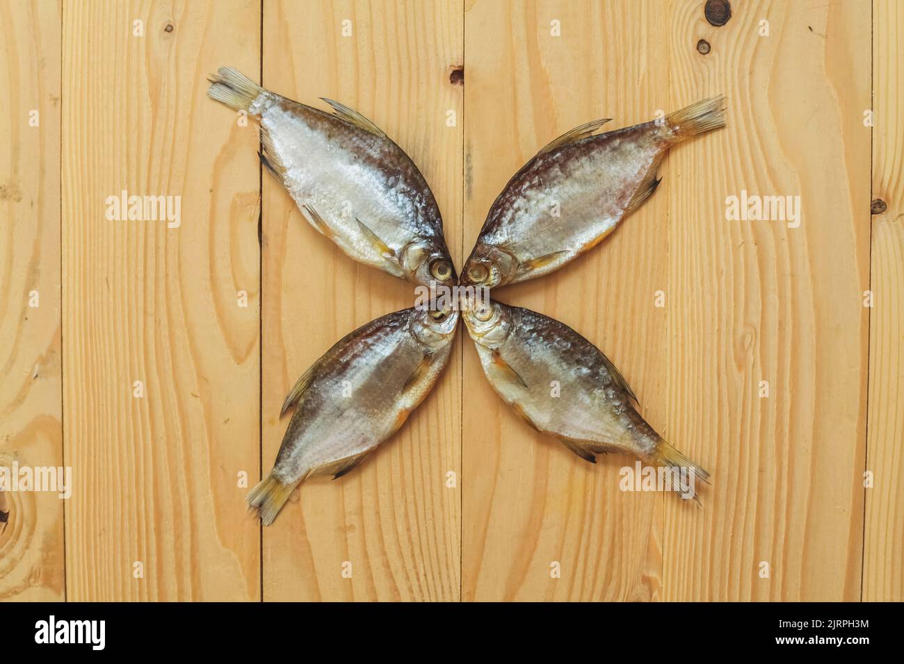 Dried salted fish on a wooden background. The fish is completely salted ...