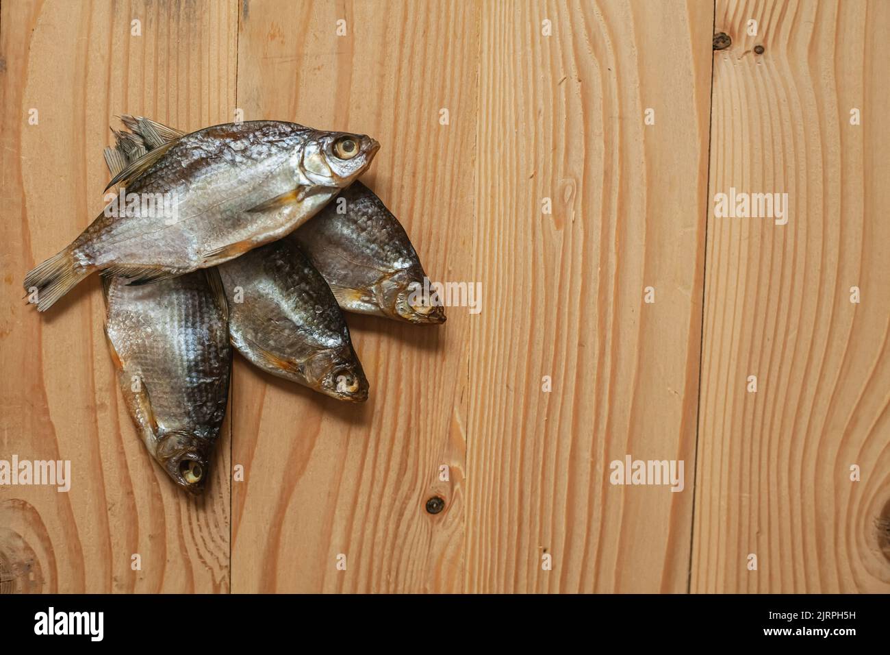 Dried salted fish on a wooden background. The fish is completely salted ...