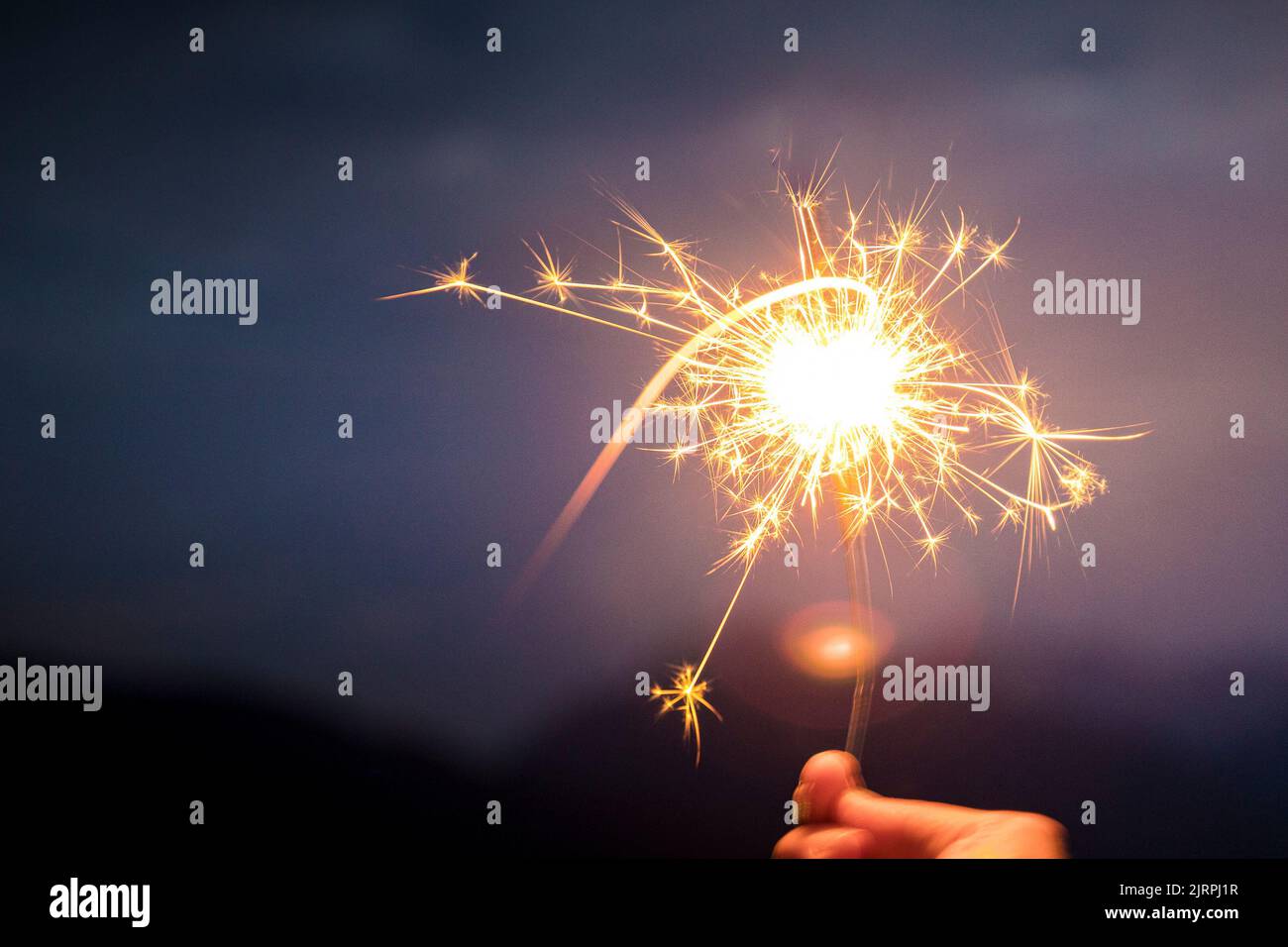 Hand holding a sparkler, or bengal fire stick, burning in outdoor ...