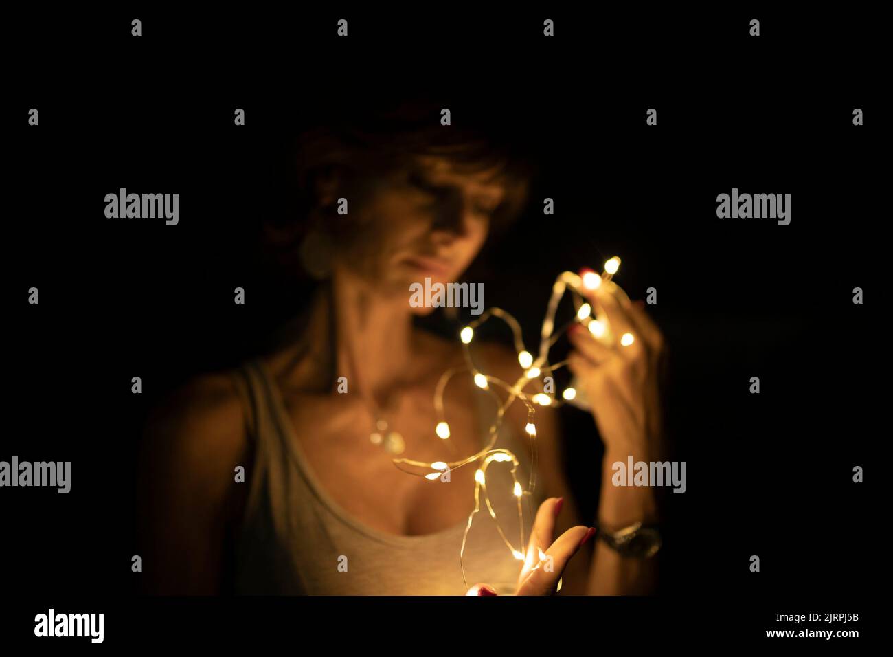 Beautiful caucasian woman, blurred face, holding string lights in the ...