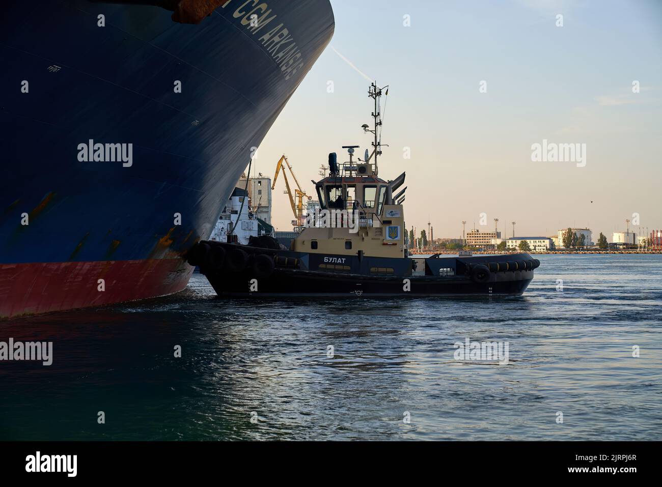 Odessa, Ukraine SIRCA 2019: A tugboat pushes container ship at port terminal. Container ship in ...