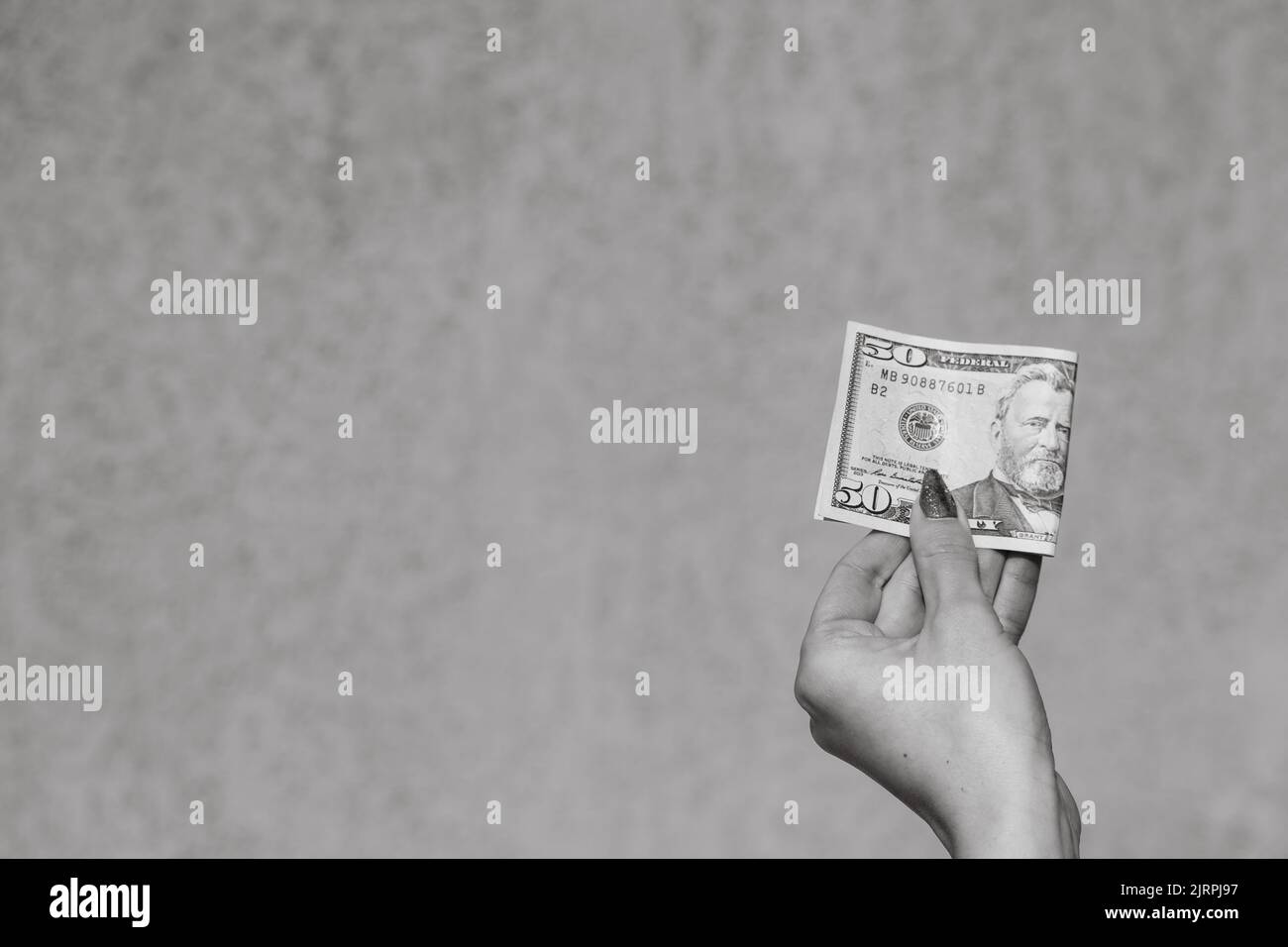 A grayscale closeup of a hand holding USD banknotes - perfect for ...
