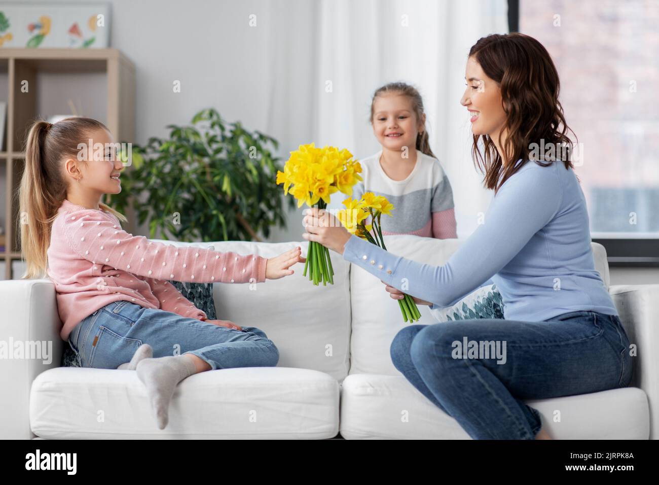 daughters giving daffodil flowers to happy mother Stock Photo - Alamy
