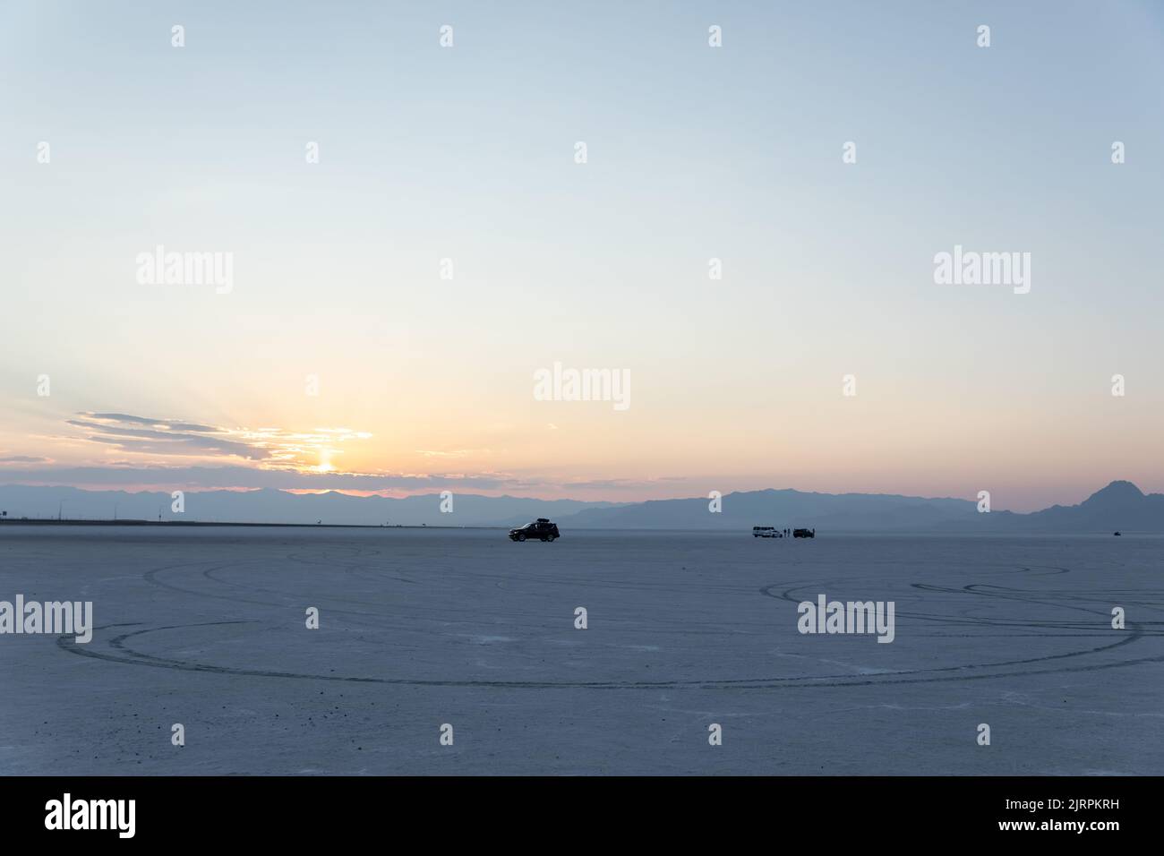 Car on the Bonneville Salt Flats in Utah at sunset with tire tracks ...