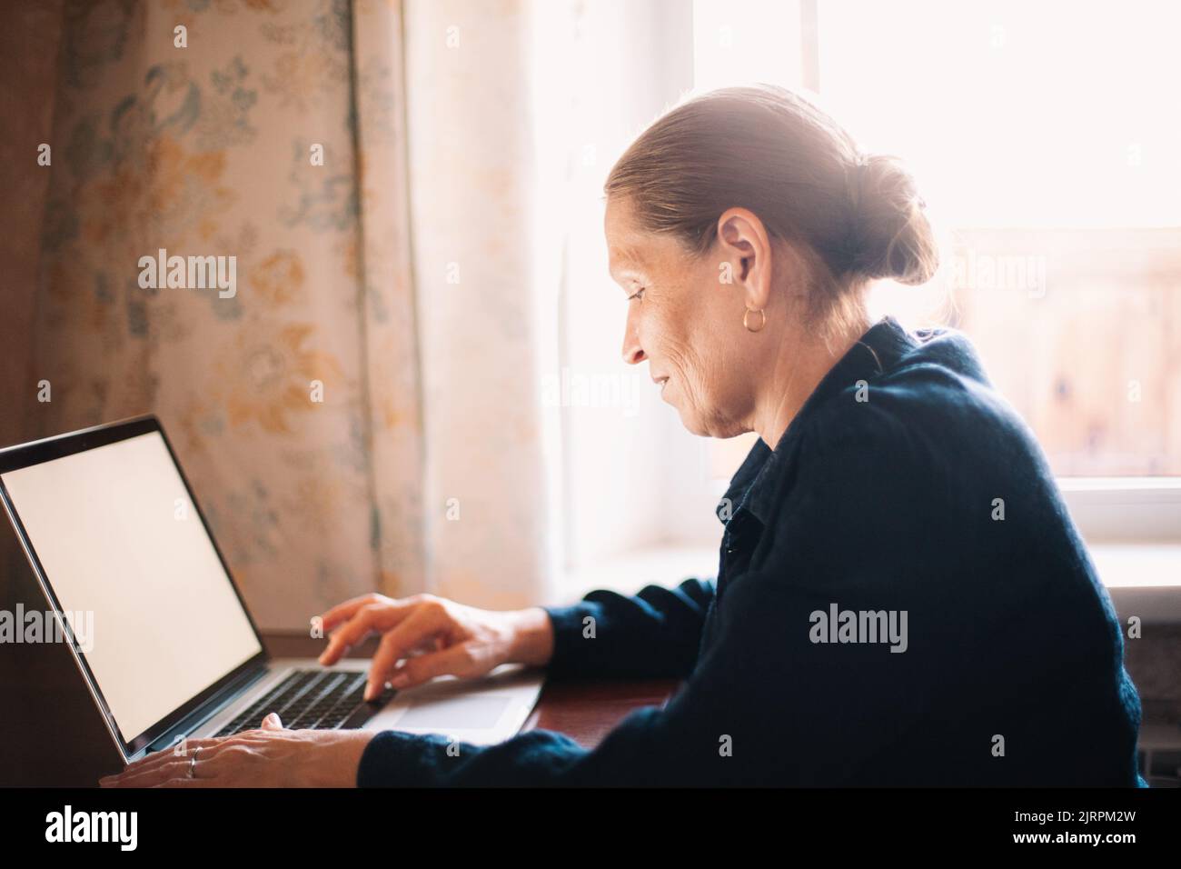 Happy mature woman using laptop computer while working at home Stock ...