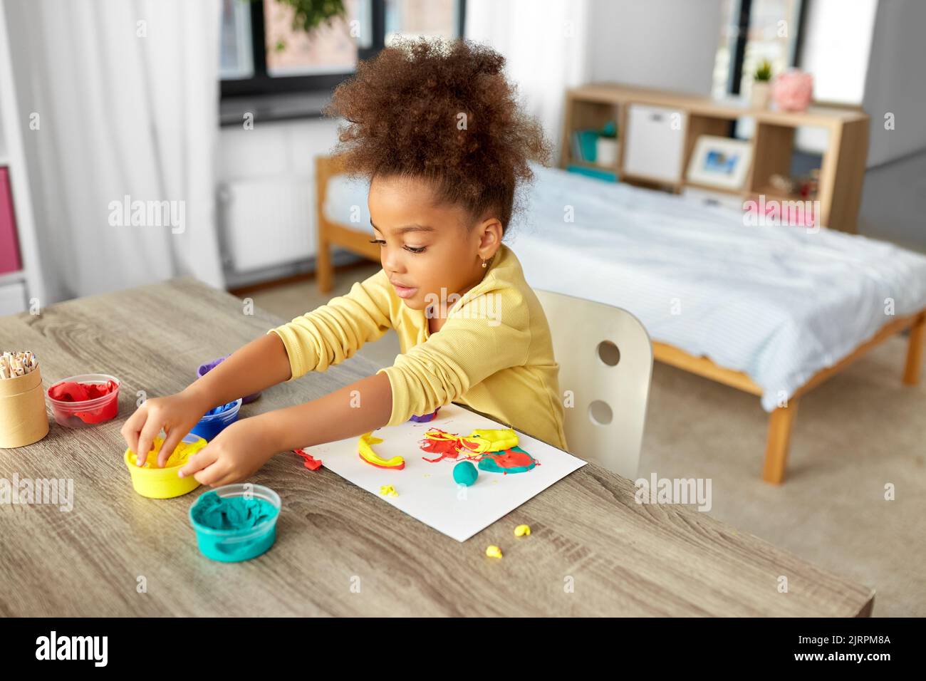 little girl with modeling clay playing at home Stock Photo - Alamy