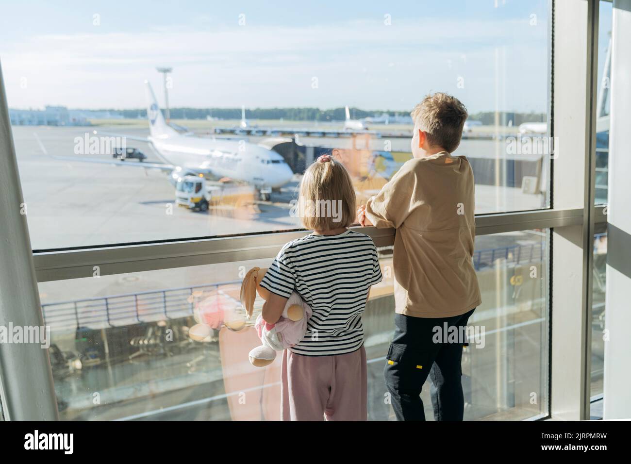Children at the airport looking out the window at the plane Stock Photo ...