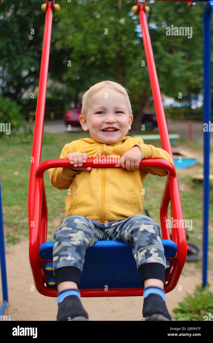 Happy boy on swings at playground Stock Photo - Alamy