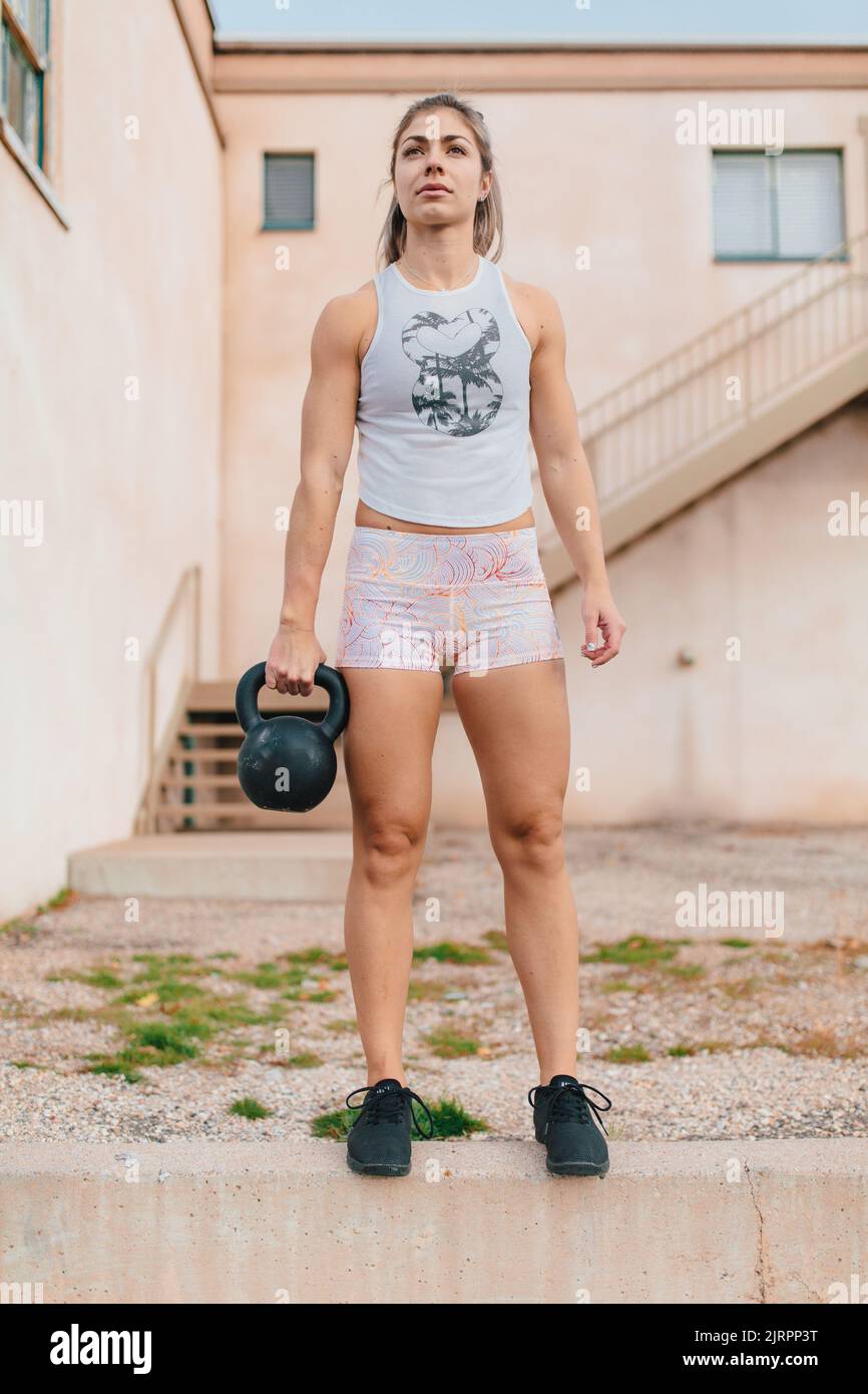 Woman in workout clothes holding kettlebell outside for a workou Stock ...