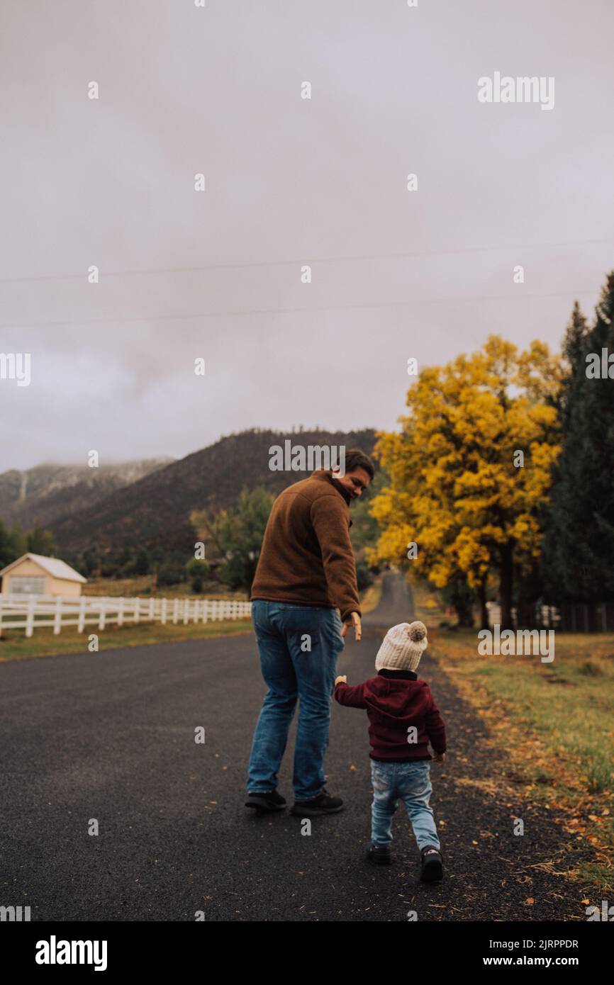 dad reaching out to toddler outside in the fall during cloudy da Stock ...