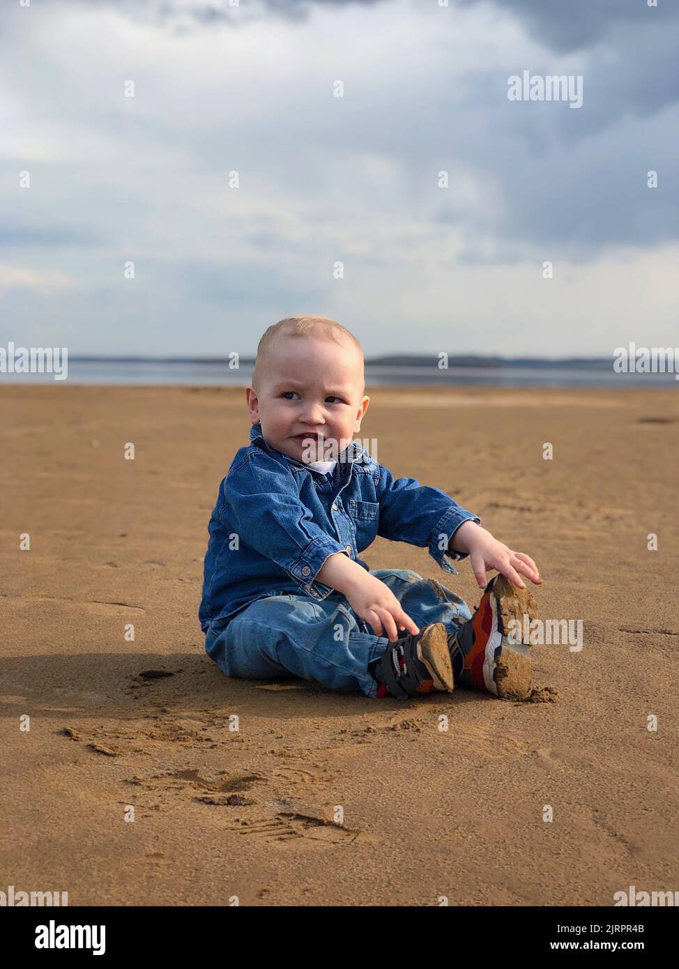 Little boy sitting on river bank Stock Photo - Alamy