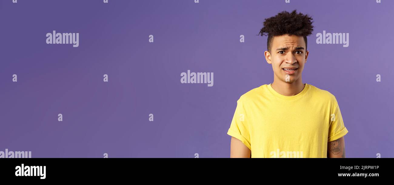 Close-up portrait of awkward and embarrassed young hispanic guy looking ...