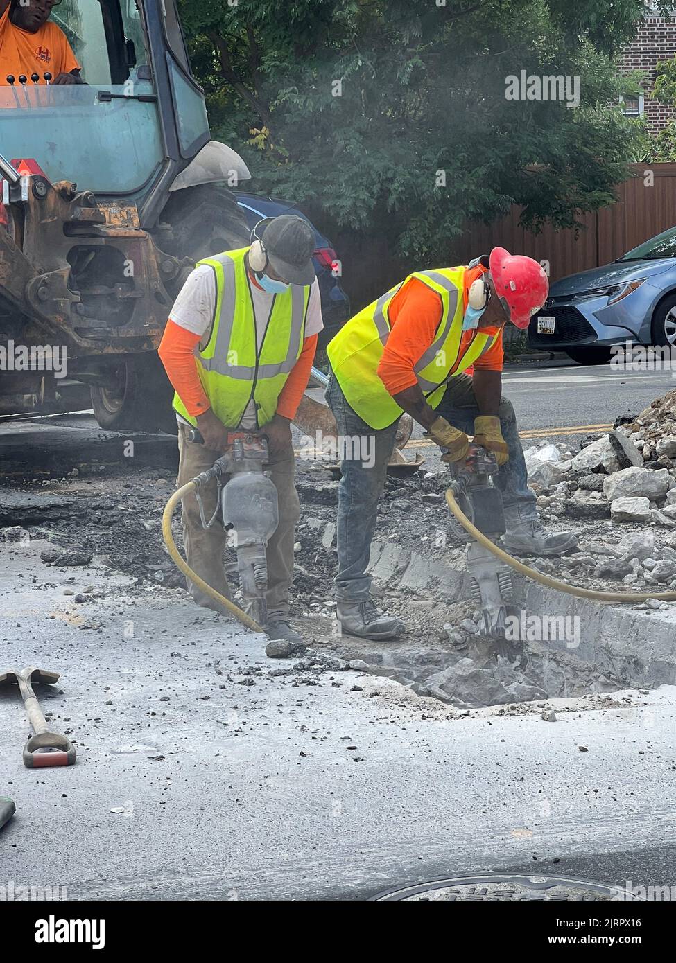 Street repair workers drilling and breaking up the cement on a hot ...