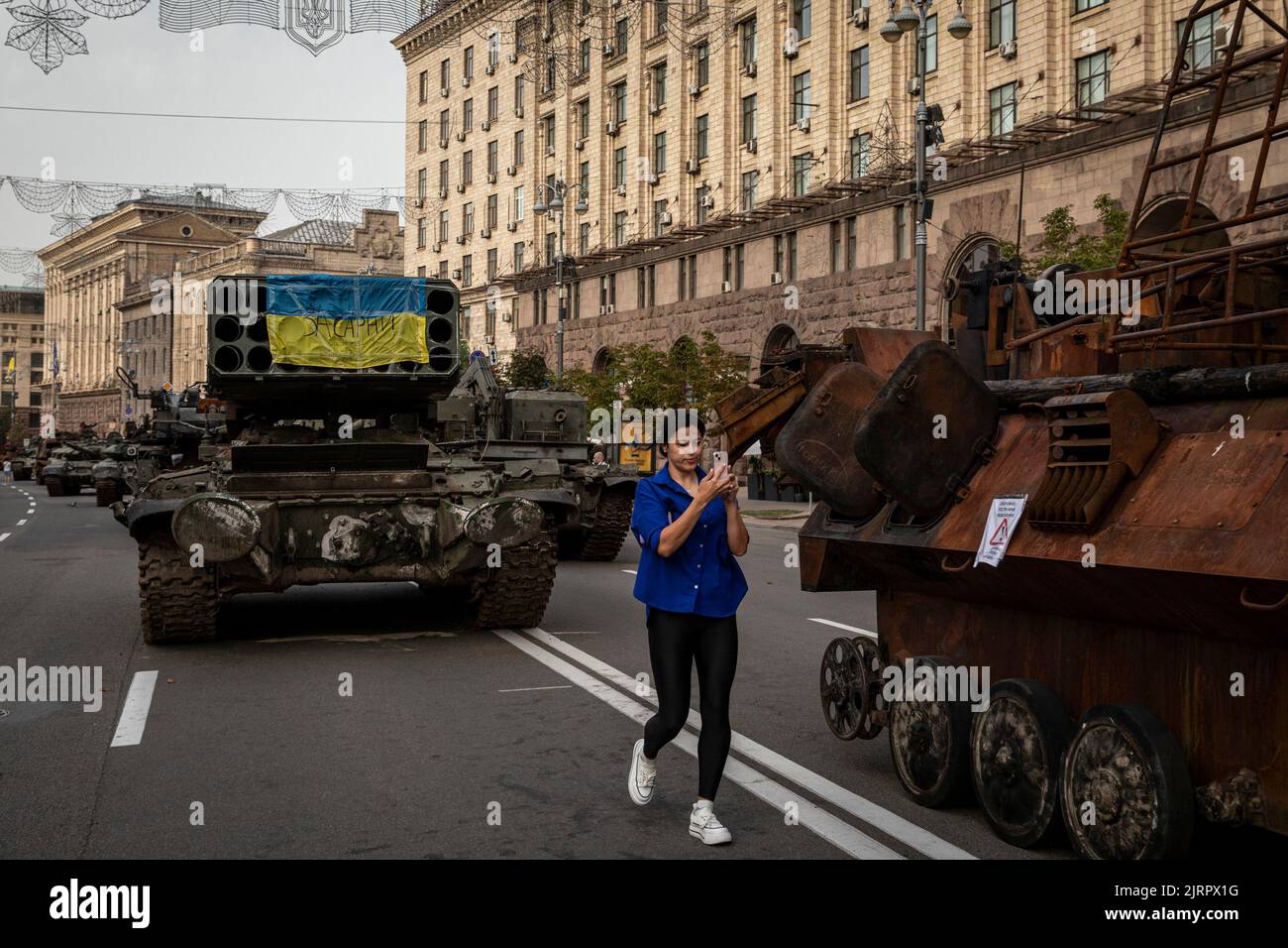 A woman takes a video of destroyed Russian military vehicles in Kyiv ...